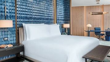 Quarto de hotel com uma cama grande, mesas de cabeceira, escrivaninha e uma cadeira.