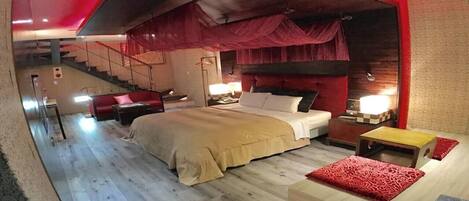 Um quarto com uma cama grande, uma escrivaninha, uma cadeira e uma mesa pequena.