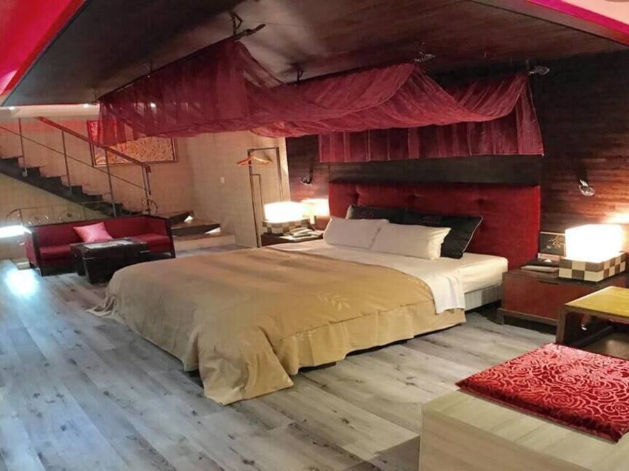 Um quarto com uma cama grande, uma escrivaninha, uma cadeira e uma mesa pequena.