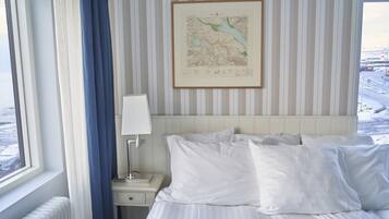 Quarto de hotel com cama, mesa de cabeceira, luminária, janela e mapa na parede.