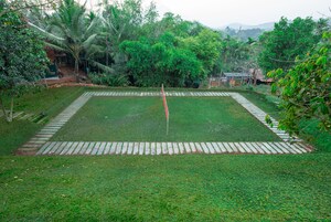 Uma área gramada com um caminho central e vegetação ao redor.