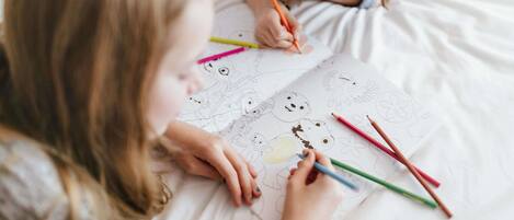 Duas crianças desenhando em uma folha de papel branca.