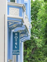 Placa de hotel com 'HOTEL' e 'BELLE EPOQUE' na fachada de um prédio.