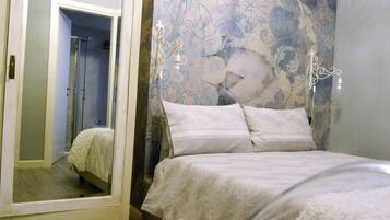 Quarto com cama, espelho e papel de parede estampado com flores.