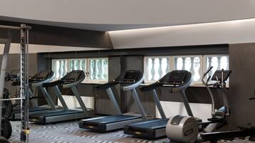 Uma academia com esteiras, um banco de musculação e um remo.