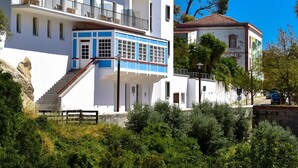 Um edifício de vários andares com varandas, uma escadaria e vista para o verde ao redor.