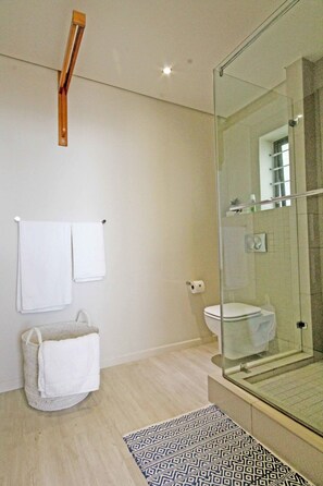 Um banheiro moderno com box de vidro, vaso sanitário e porta-toalhas.