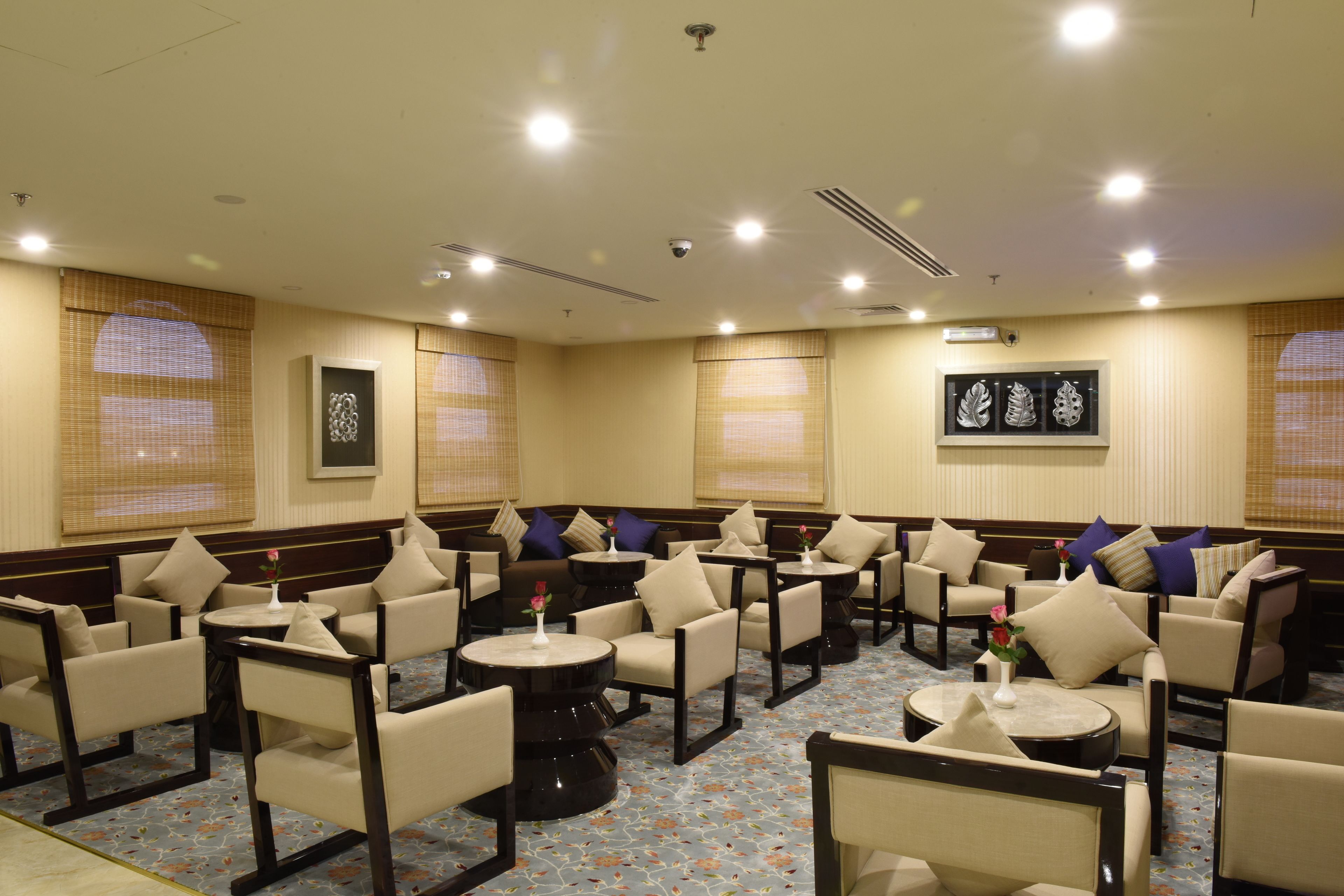 Um saguão de hotel com diversas áreas de estar, incluindo sofás e poltronas, disposto em um espaço amplo.