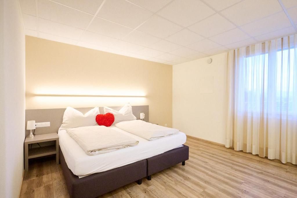 Quarto de hotel com cama, mesa de cabeceira e janela com cortinas.