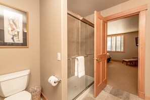 Casa de banho com sanita, cabine de duche em vidro e um porta-toalhas.