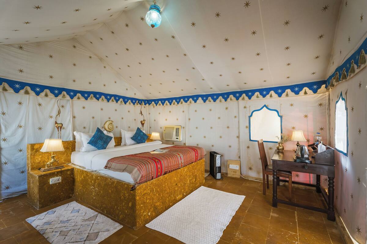Quarto com cama, mesas de cabeceira, escrivaninha e cadeira.