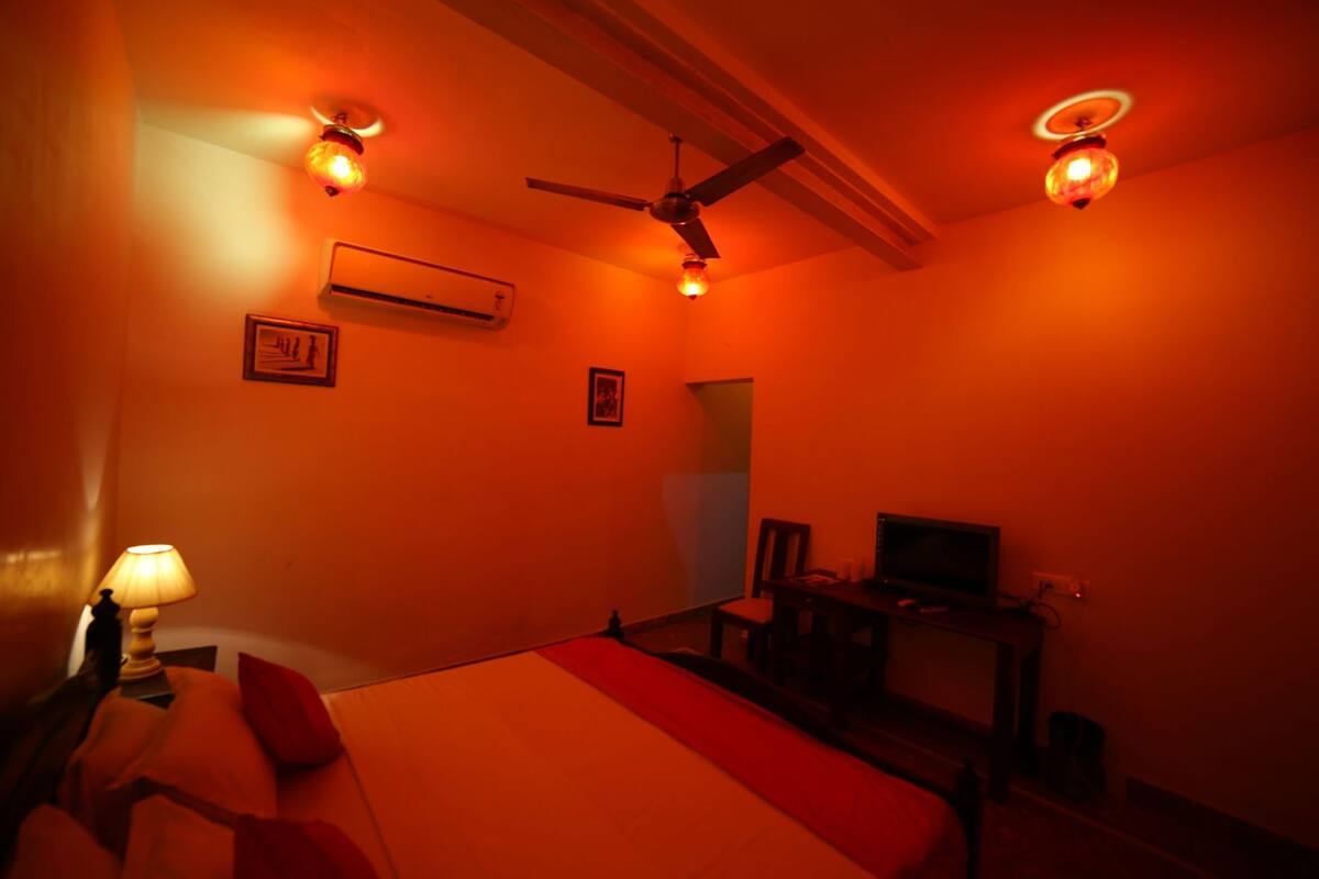 Um quarto com uma cama, uma escrivaninha, um ventilador de teto e um aparelho de ar condicionado.