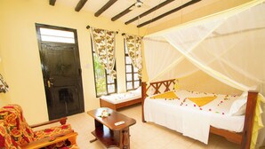Quarto com cama, cadeira, mesa pequena, porta e janelas com cortinas.