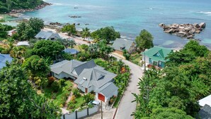 Uma área residencial costeira com casas, vista clara para o mar e um litoral rochoso.