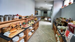 Disposição de buffet com diversos alimentos e utensílios sobre prateleiras e mesas de madeira.