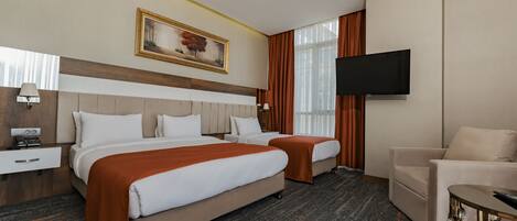 Quarto de hotel com duas camas, um sofá, uma TV e um quadro na parede.