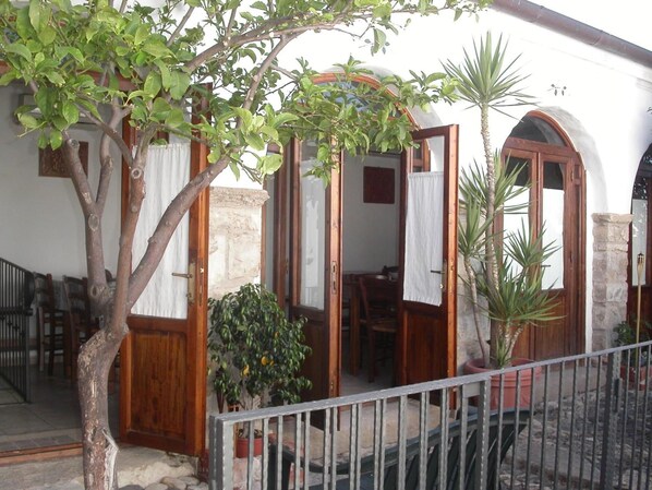 Um edifício rústico com porta de madeira, parede de pedra e guarda-corpo de metal.