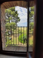 Varanda com grade de metal vista para um jardim com árvores e céu claro.