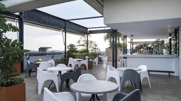 Terraço no telhado com área de estar ao ar livre, bar e plantas em vasos.