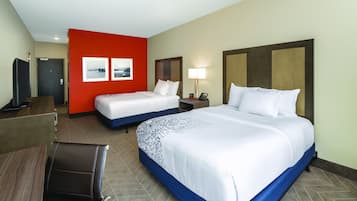 Quarto de hotel com duas camas, uma escrivaninha, uma cadeira e uma televisão.