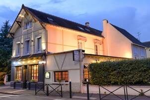 Um edifício de dois andares com estilo arquitetônico clássico, com grandes janelas e uma placa indicando que funciona como hotel, restaurante e pensão.