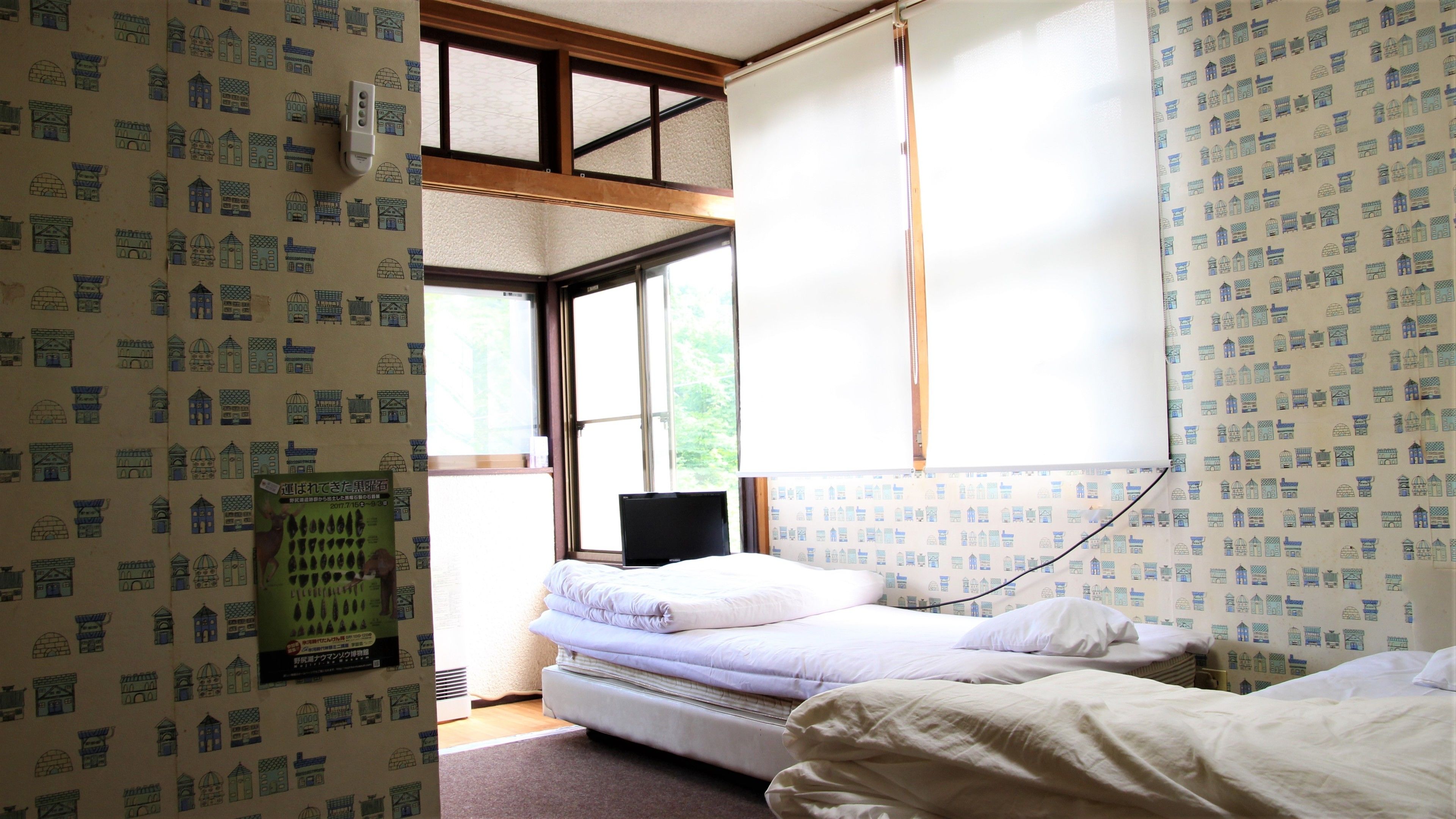 Um quarto com uma cama, uma janela e uma parede com papel de parede estampado.