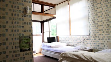 Um quarto com uma cama, uma janela e uma parede com papel de parede estampado.
