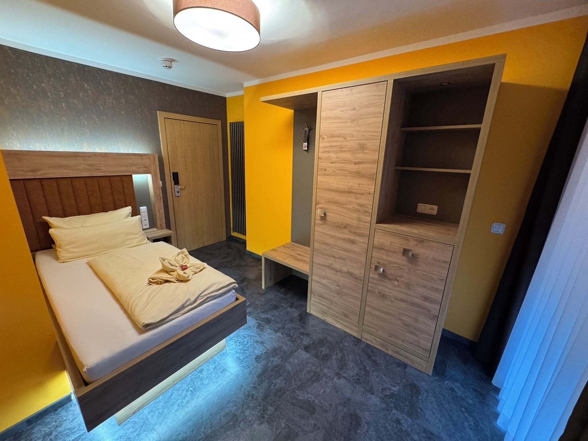 Quarto com cama, guarda-roupa e um pequeno espaço de estar.