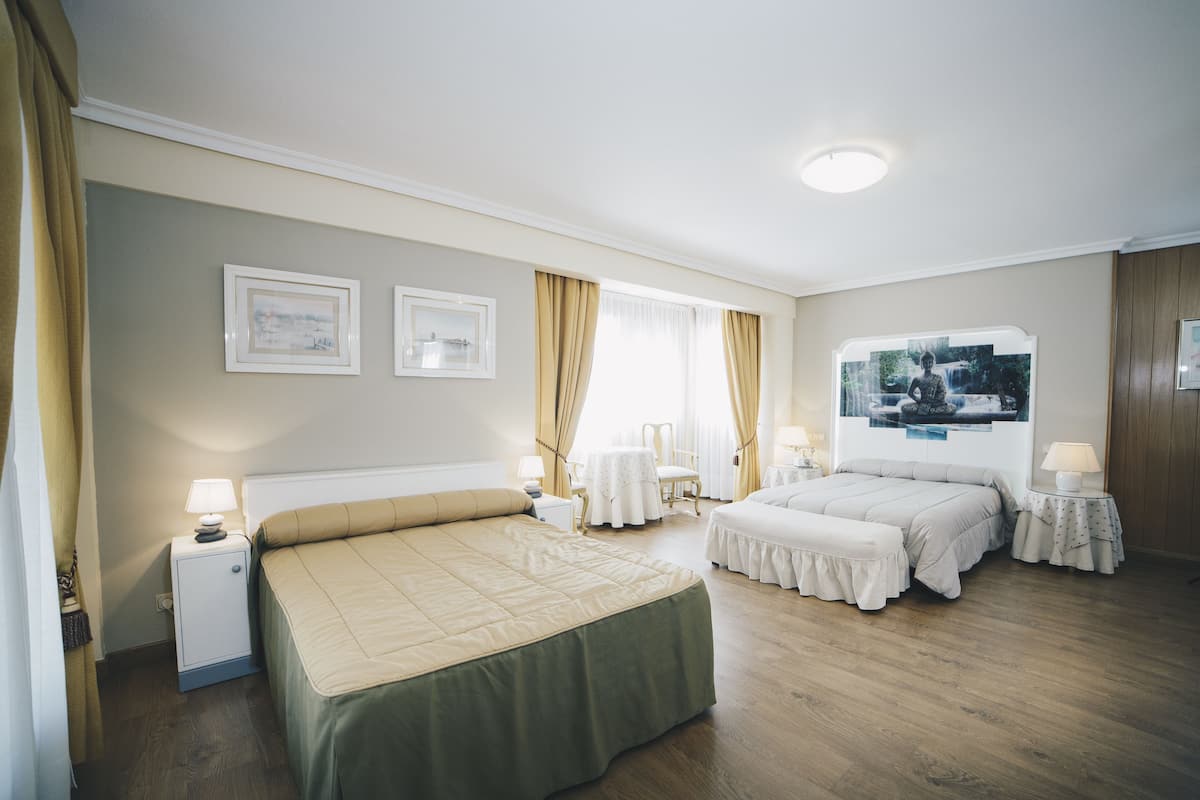Quarto de hotel com cama, mesas de cabeceira, uma cadeira e escrivaninha.