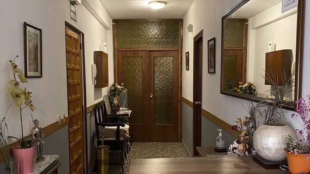 Um corredor com balcão de madeira, espelho e porta com painéis de vidro jateado.