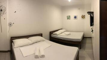 Quarto de hotel com duas camas, um painel de cabeceira de madeira, uma televisão fixada na parede e obras de arte.