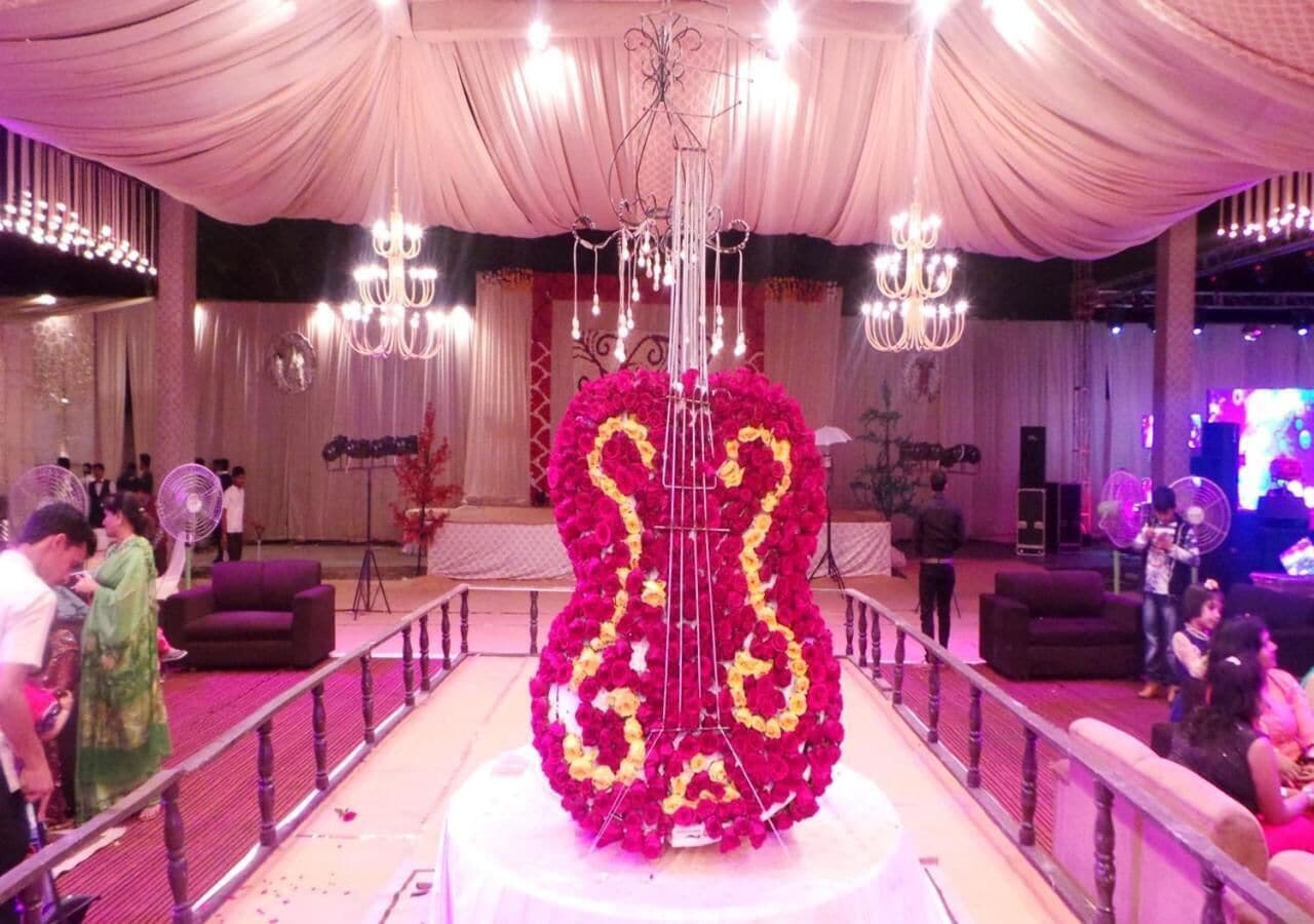 Palco com grande arranjo floral em formato de guitarra, cercado por grades e ventiladores.
