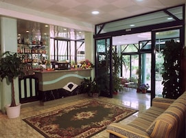Um lobby com área de bar, assentos e plantas em vasos.