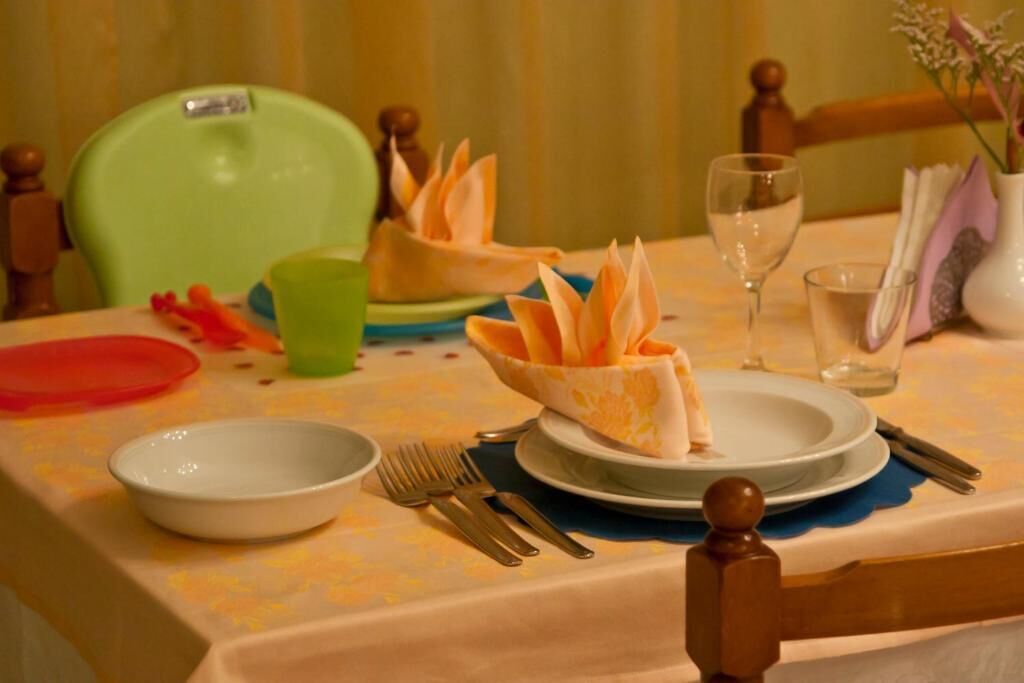 Uma mesa de jantar posta com pratos, talheres e um copo de água.