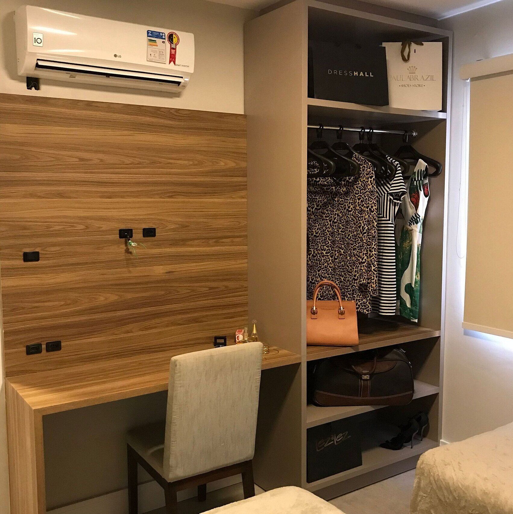 Um closet espaçoso com roupas penduradas, uma cadeira e um aparelho de ar condicionado.