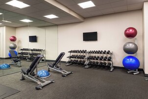 Academia com equipamentos de ginástica, halteres e bolas de exercício.