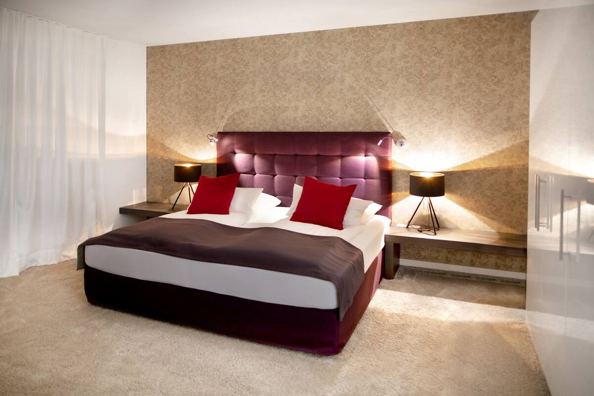 Um quarto moderno com uma cama grande, duas mesas de cabeceira e uma cabeceira com iluminação embutida.