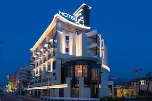 Um hotel moderno com uma placa grande que diz "HOTEL", várias varandas e fachada de vidro curva.