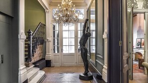Uma entrada imponente com um candelabro, uma estátua e uma escadaria.