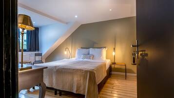 Quarto com cama, mesas de cabeceira, escrivaninha e luminária.