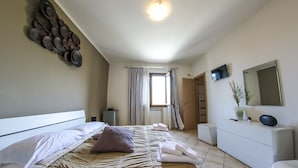 Um quarto moderno com cama, cômoda, televisão e janela com cortinas.