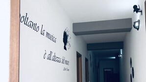Um corredor com um radiador, uma cadeira branca e uma mesa com uma planta.