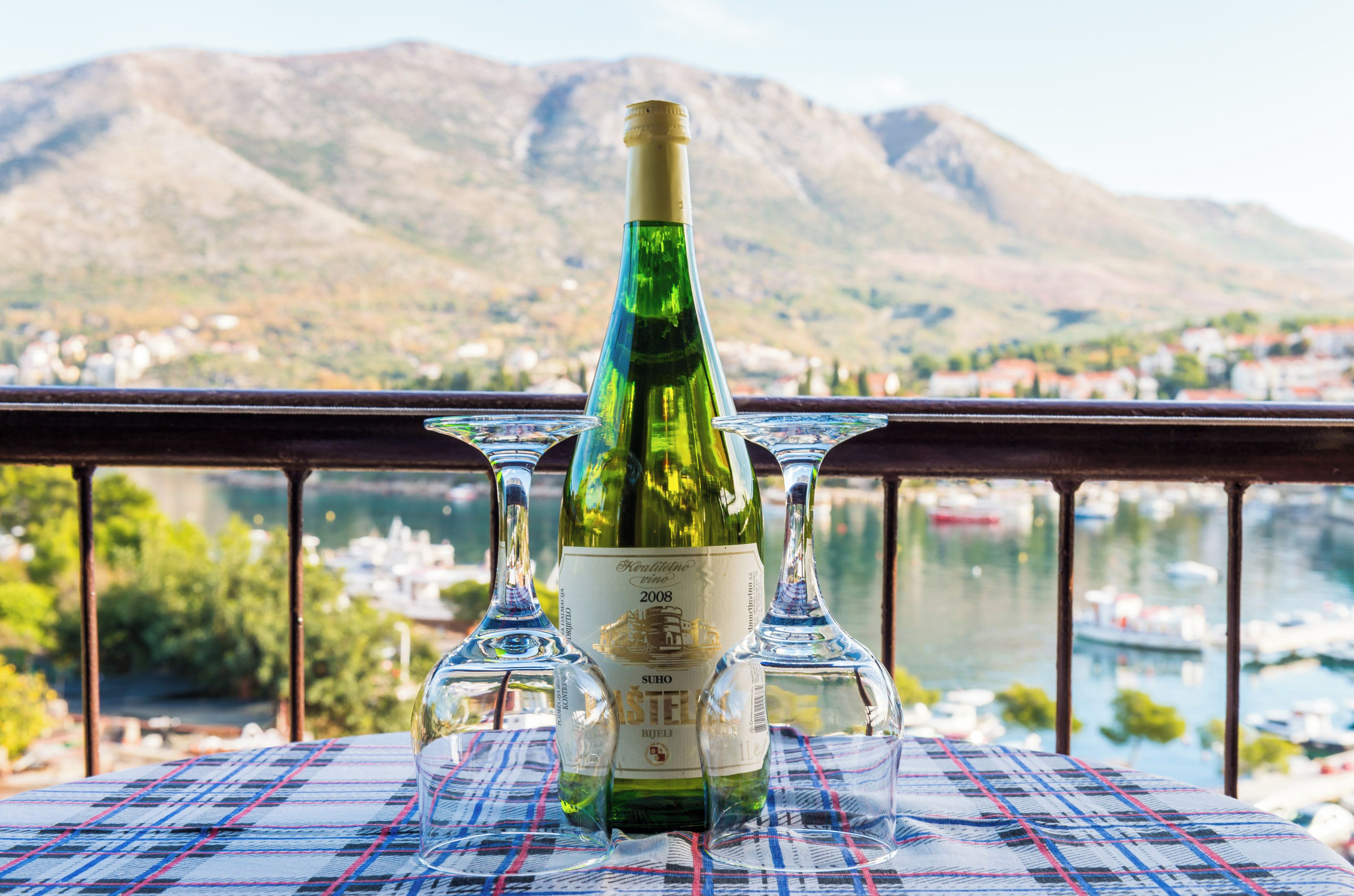 Uma garrafa de vinho Suho sobre uma mesa, com vista para um lago e montanhas.