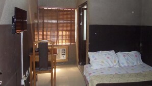 Um quarto com cama, escrivaninha e cadeira.
