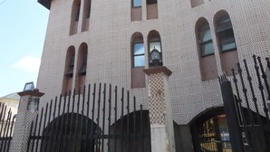 Um edifício com fachada estampada, várias janelas em arco e um portão.