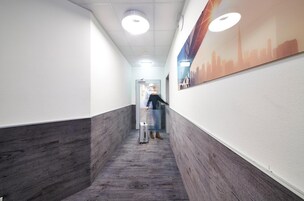 Um corredor estreito com piso de madeira, paredes brancas e um mural com vista para a cidade.