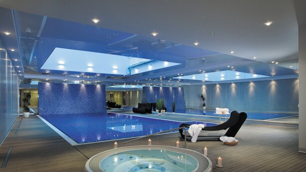 Um spa moderno com uma piscina grande, uma banheira de hidromassagem e uma área de estar com vista para a piscina.