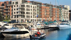 Uma marina com barcos atracados, cercada por edifícios altos com varandas.