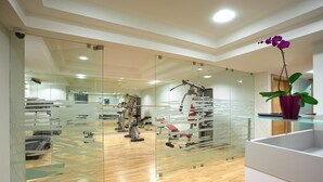 Academia moderna com paredes espelhadas, equipamentos de ginástica e piso de madeira.