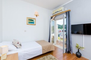 Quarto com cama, televisão, quadro e janela com cortinas.